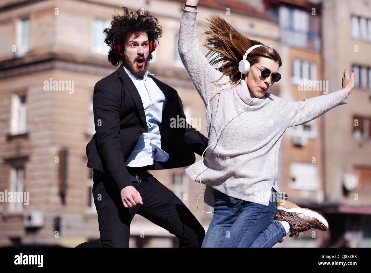 Young business colleagues dancing together with headphones after work ...