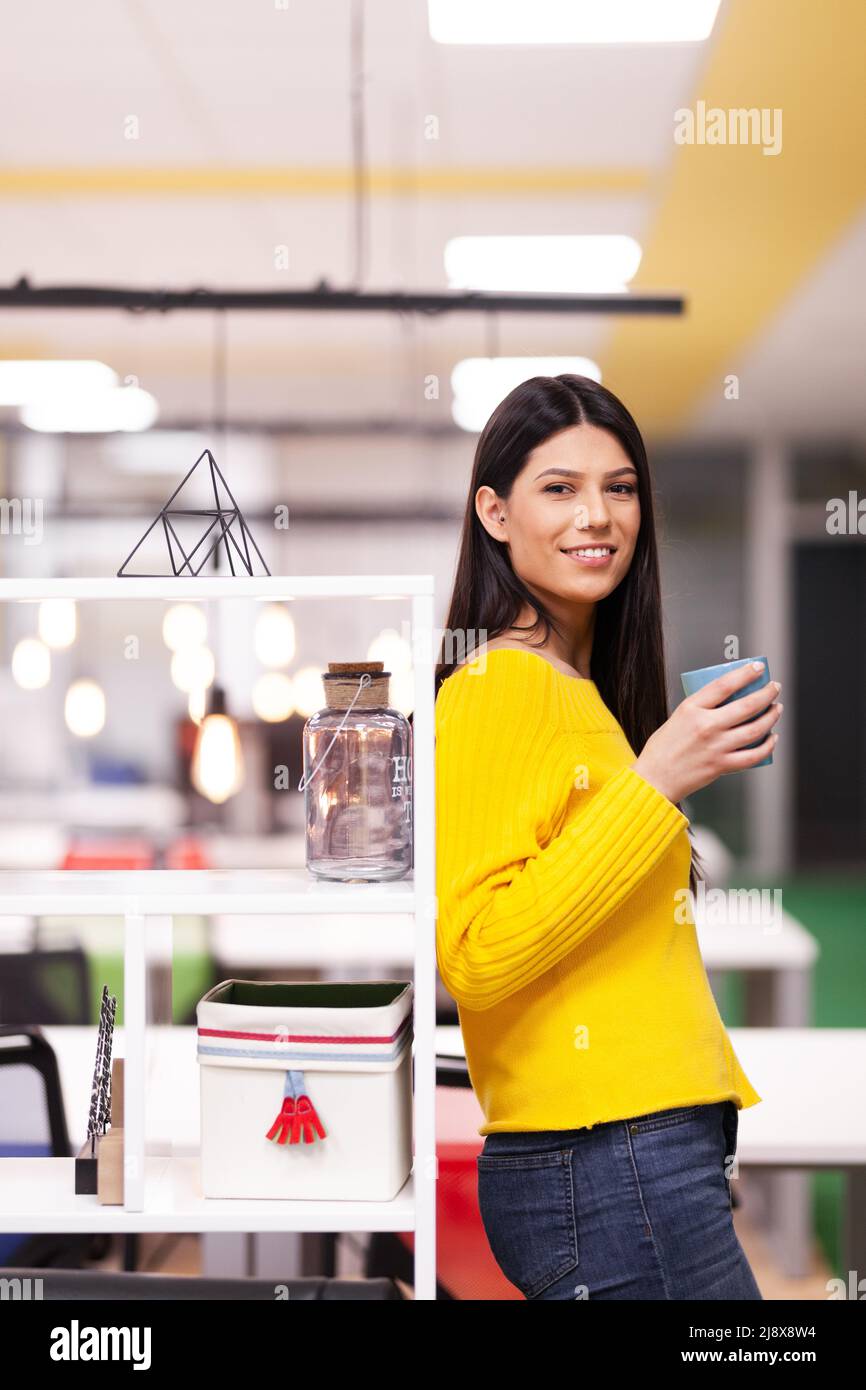 Beautiful girl drinking coffee in a modern coworking space. Successful ...