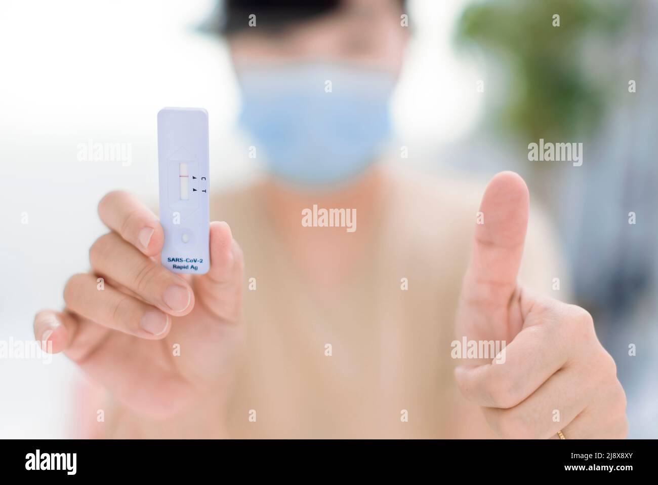 Woman showing thumbs up and antigen self test card with negative result ...