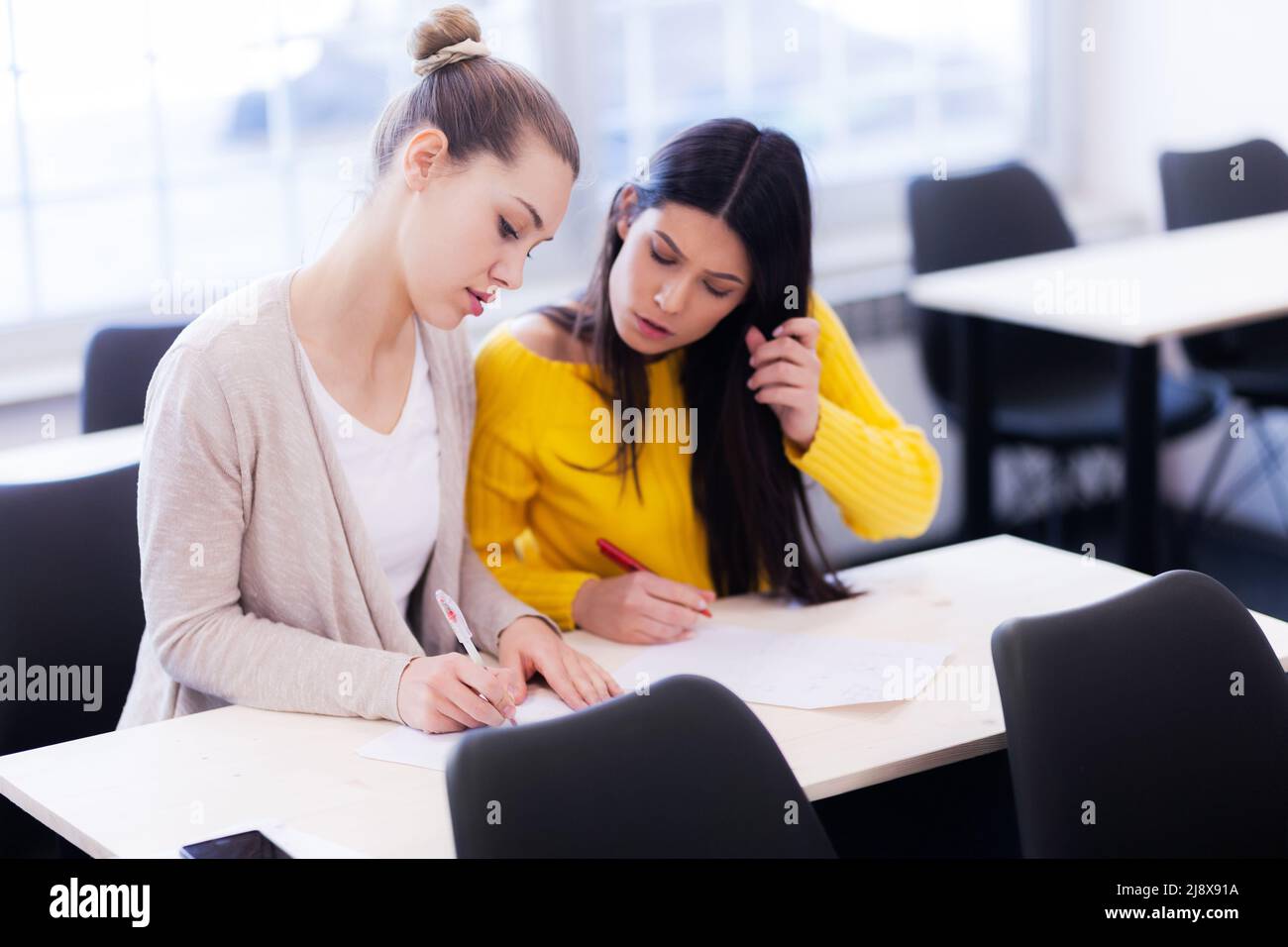 Students taking a test in a classroom. Smart young girls study at a ...