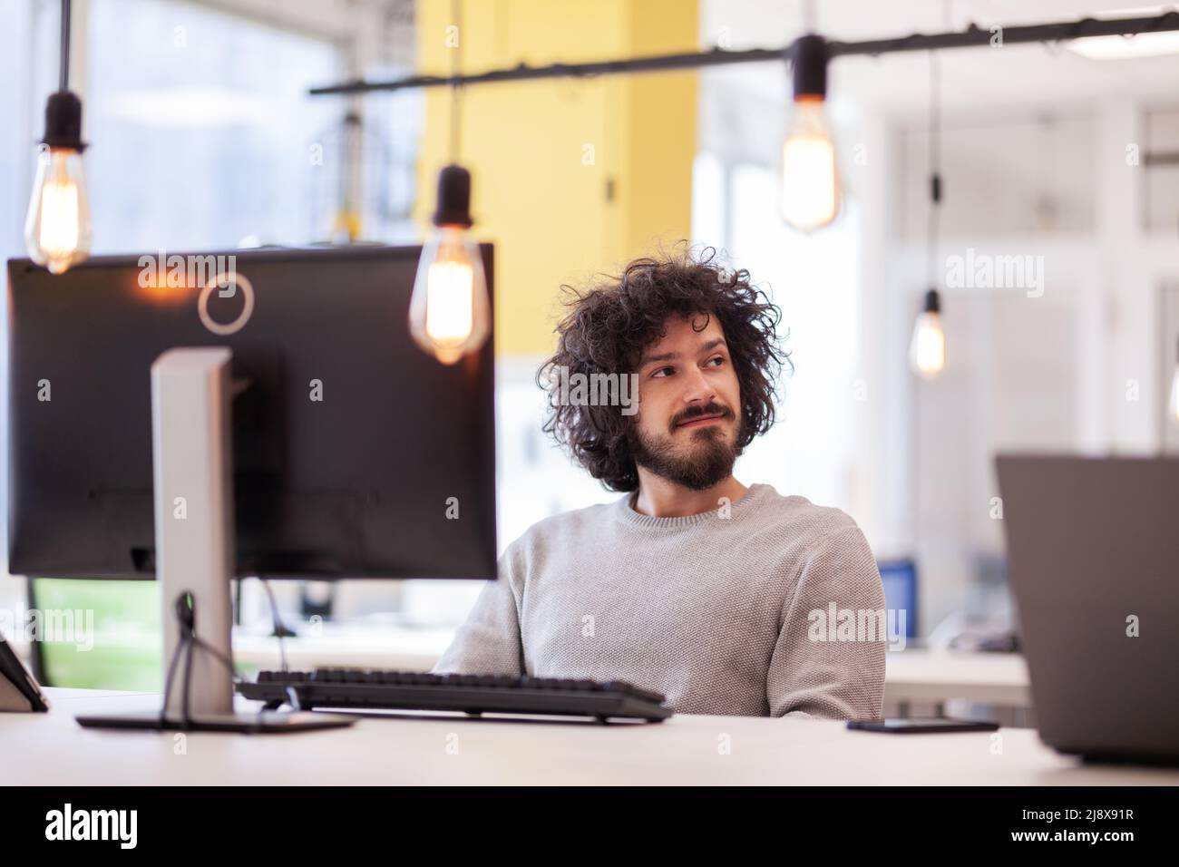 Casual businessman with clumsy hair working on desktop computer in a ...