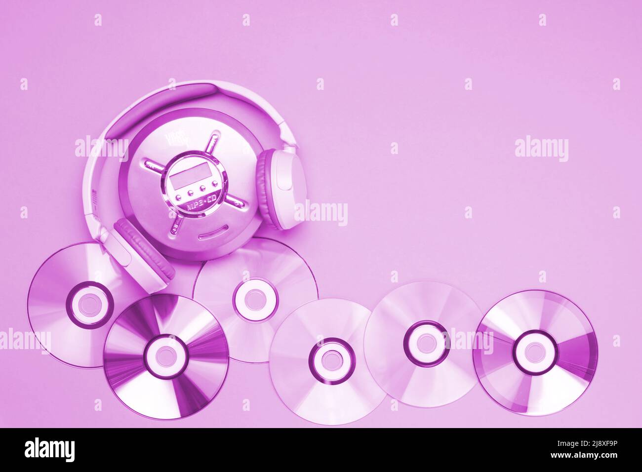 Personal compact portable CD player disks purple headphones on a pink ...