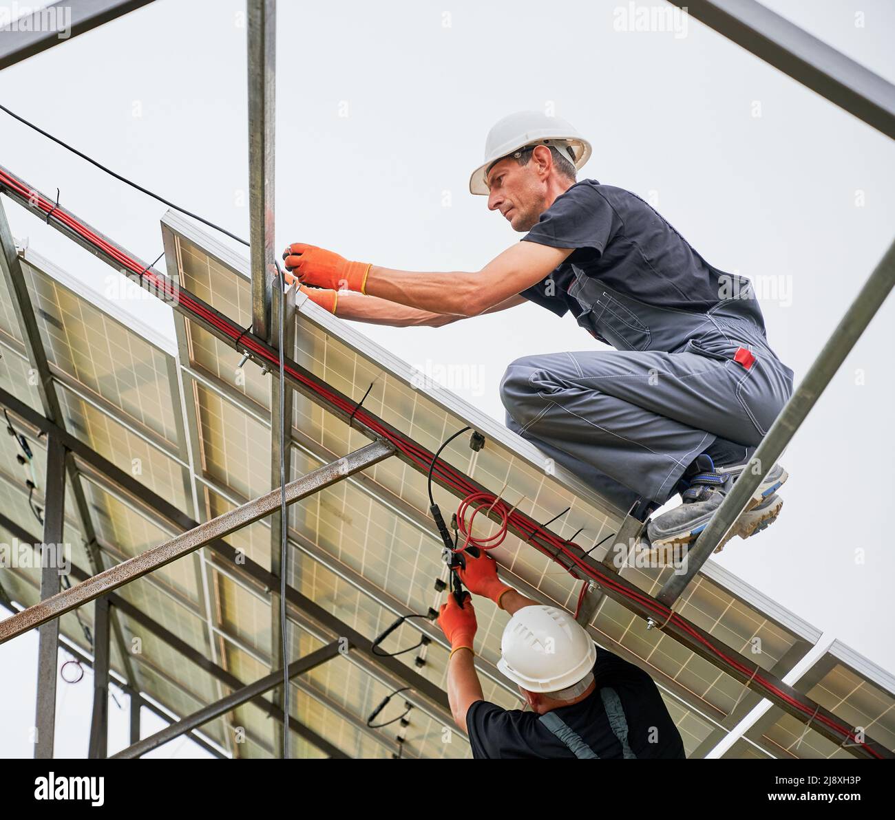 Two men in safety construction helmets installing photovoltaic solar ...