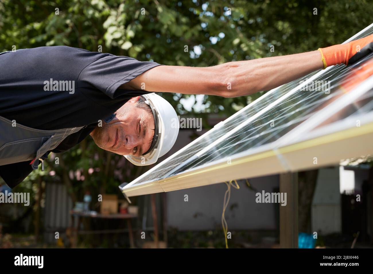Male worker in safety helmet looking at camera and winking while ...