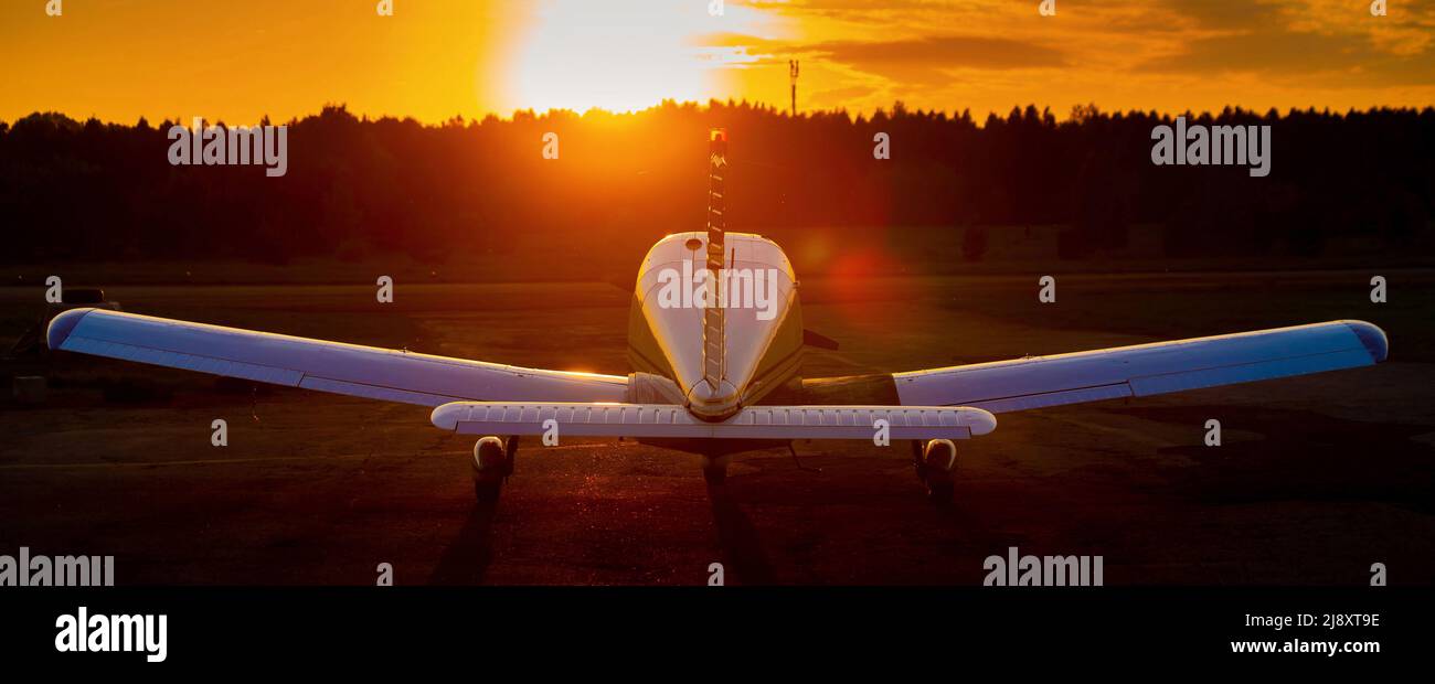 Rear view of a parked small plane on a sunset background. Silhouette of ...