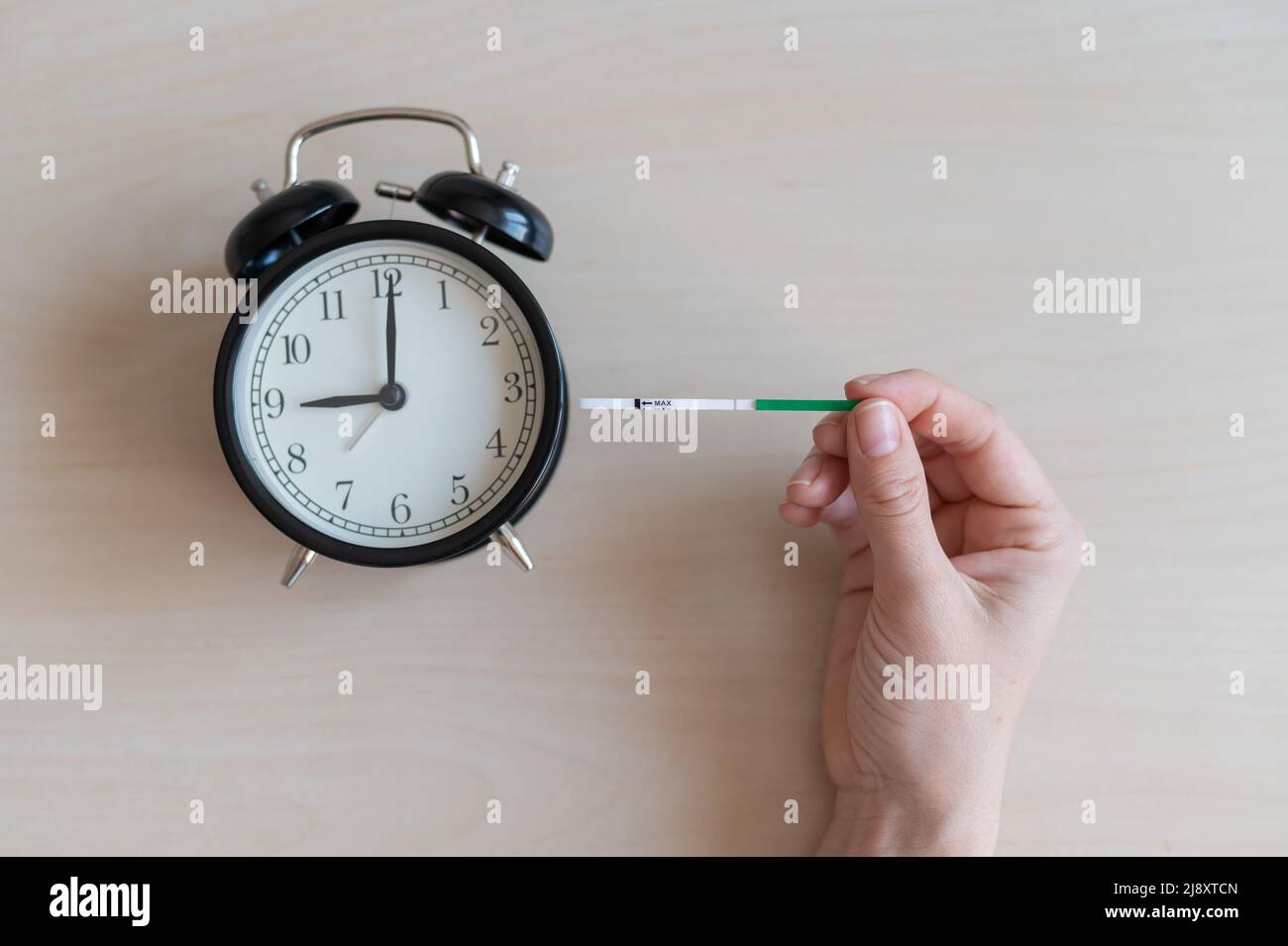 Woman holds negative ovulation test and alarm clock. Female fertility ...