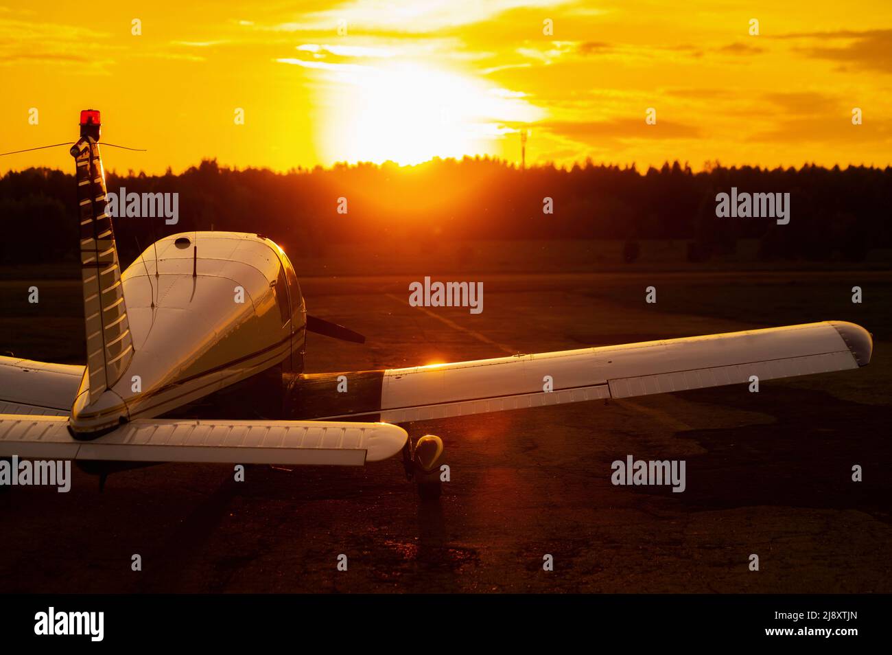 Rear view of a parked small plane on a sunset background. Silhouette of ...
