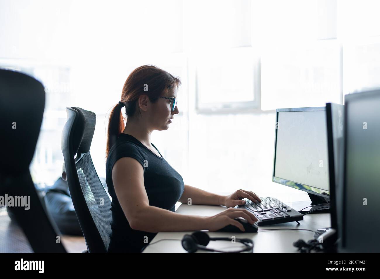 Silhouette of a caucasian business woman typing at a computer. Female employee works overtime ...