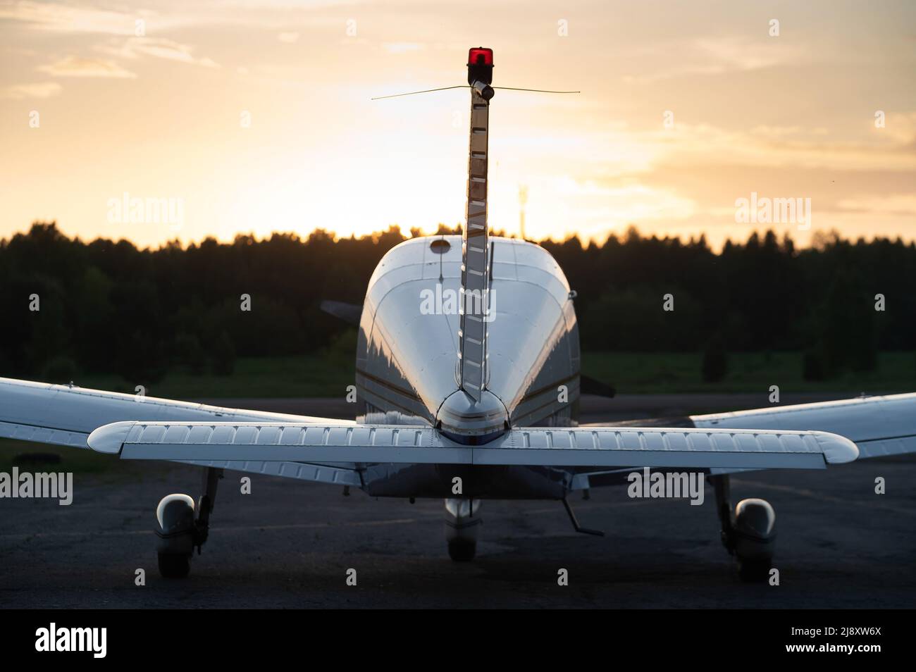 Rear view of a parked small plane on a sunset background. Silhouette of ...