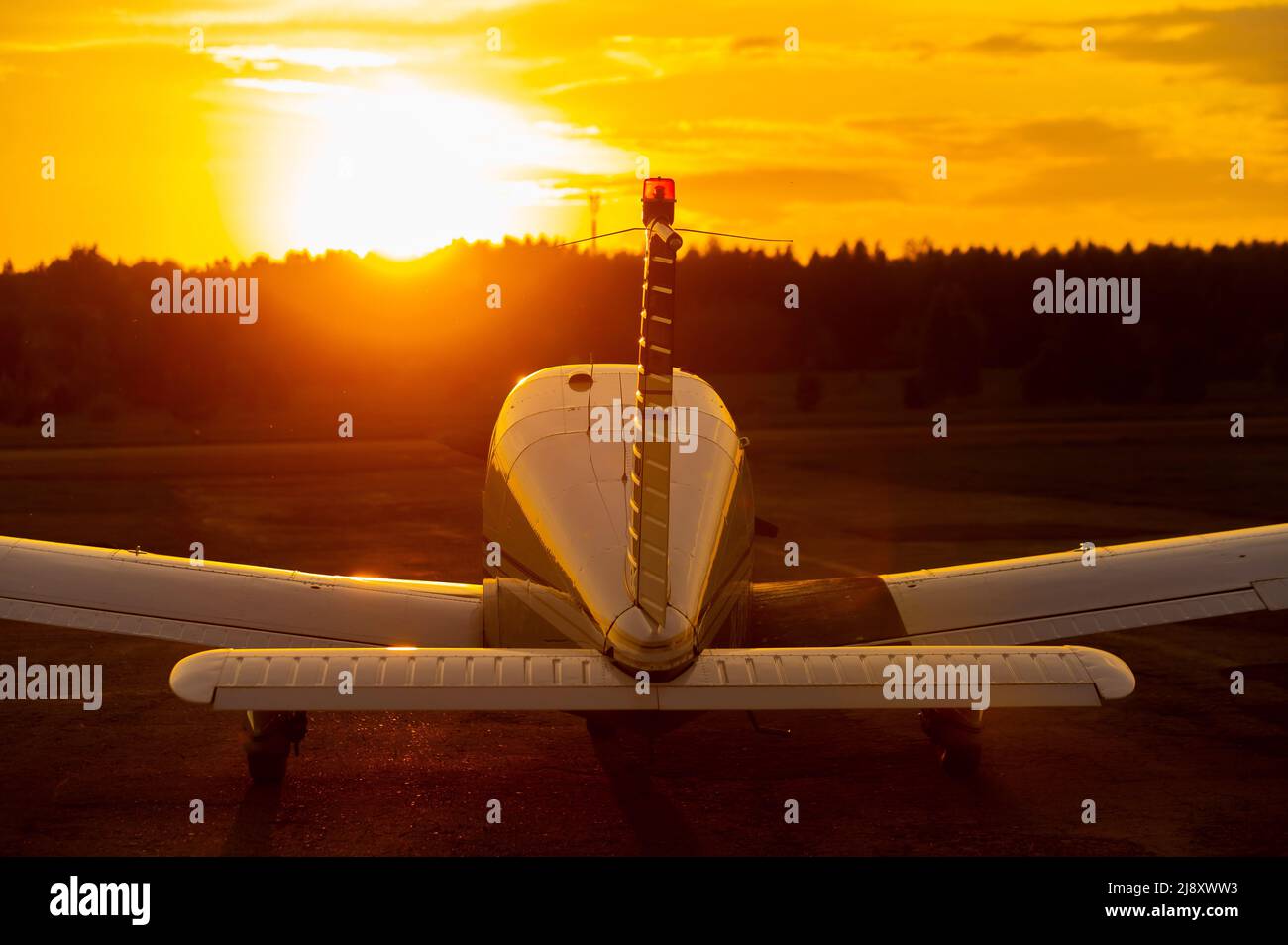 Rear view of a parked small plane on a sunset background. Silhouette of ...