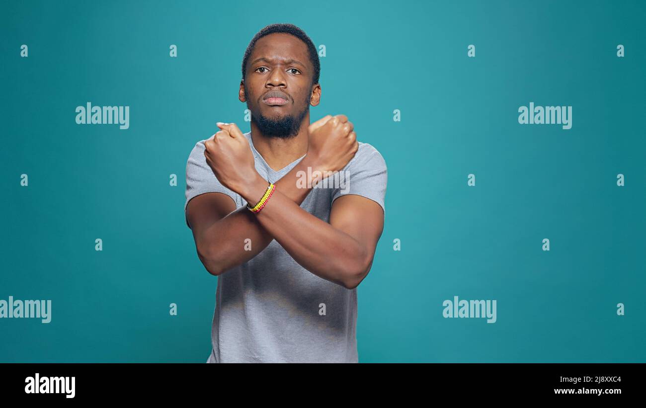 Displeased man doing stop gesture with arms on camera, showing ...