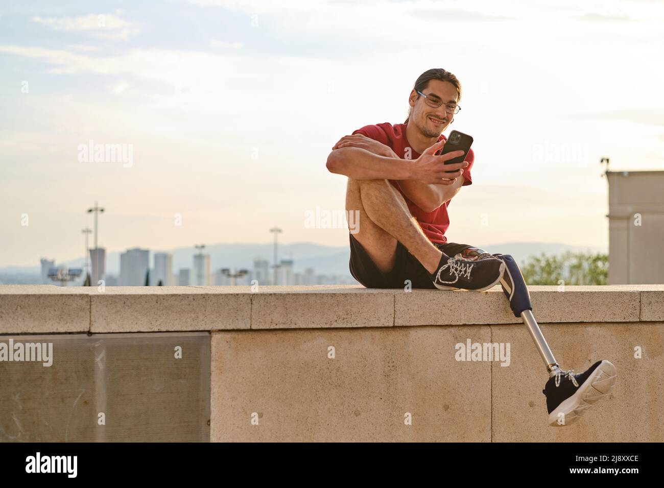 Man with a disability using his mobile phone and smiling while relaxing ...