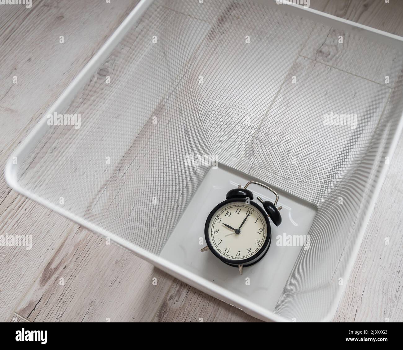 Top view of an alarm clock discarded in a white mesh metal trash bin ...