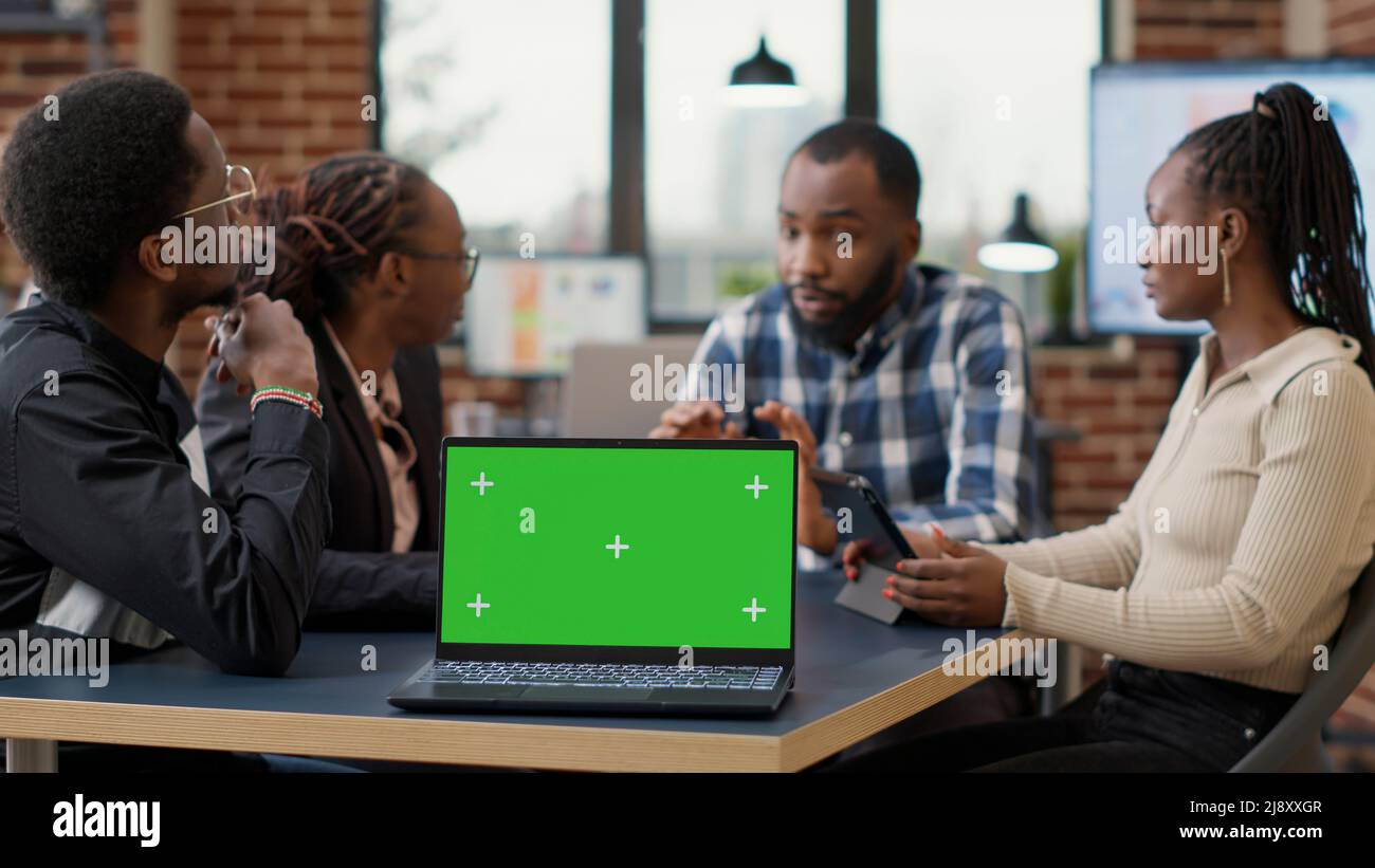 Businesspeople attending briefing meeting with greenscreen on laptop ...