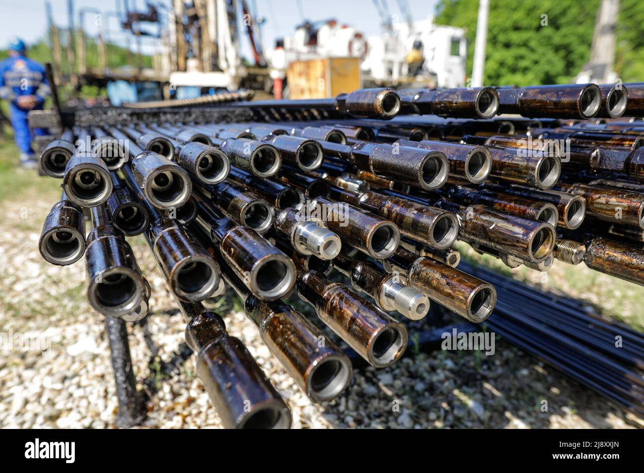Oil rig drill pipes stacked with oil industry workers in the background ...