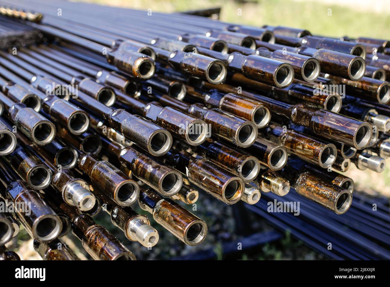 Oil rig drill pipes stacked with oil industry workers in the background ...