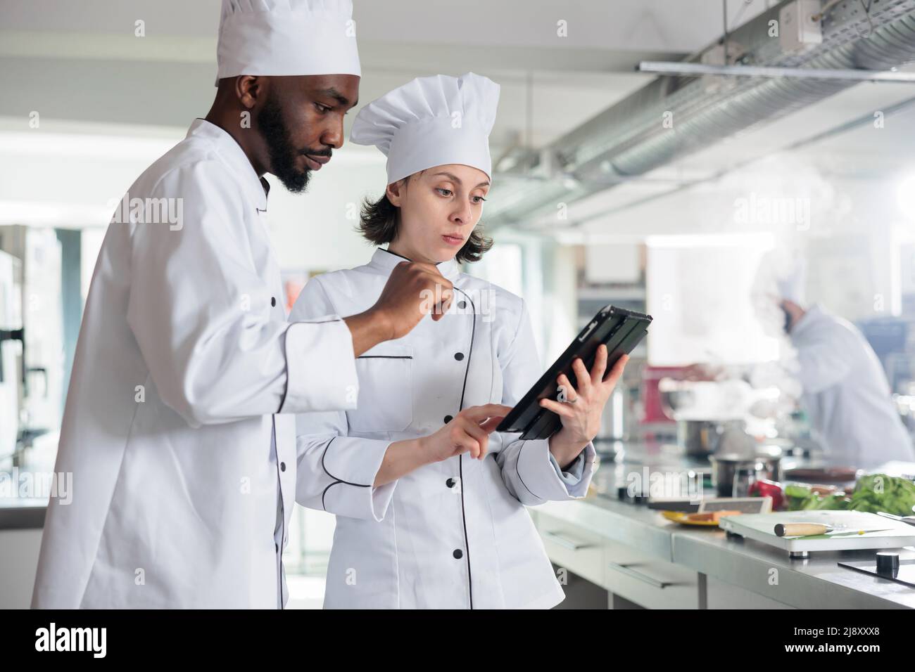 Professional chefs with wireless touchscreen device preparing ...