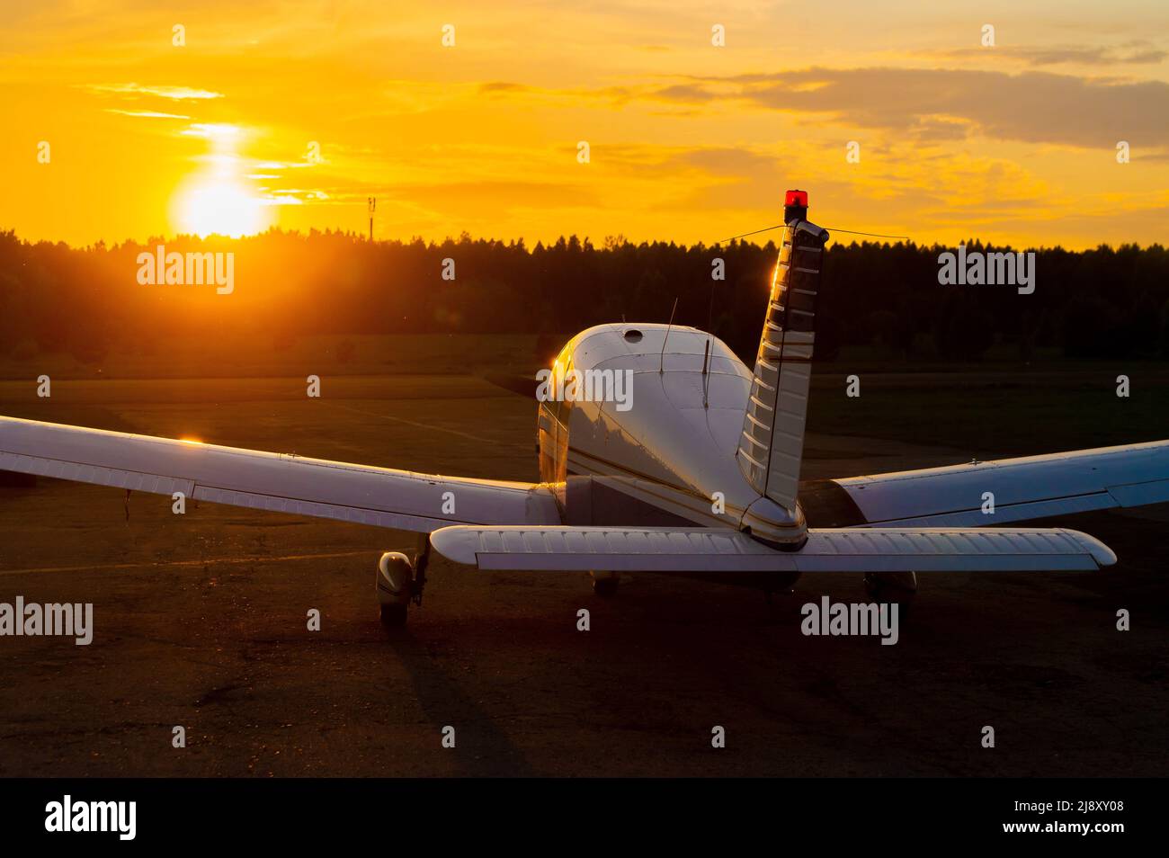 Rear view of a parked small plane on a sunset background. A silhouette ...