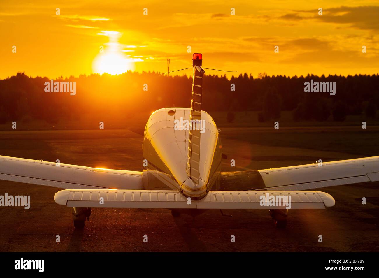Rear view of a parked small plane on a sunset background. Silhouette of ...