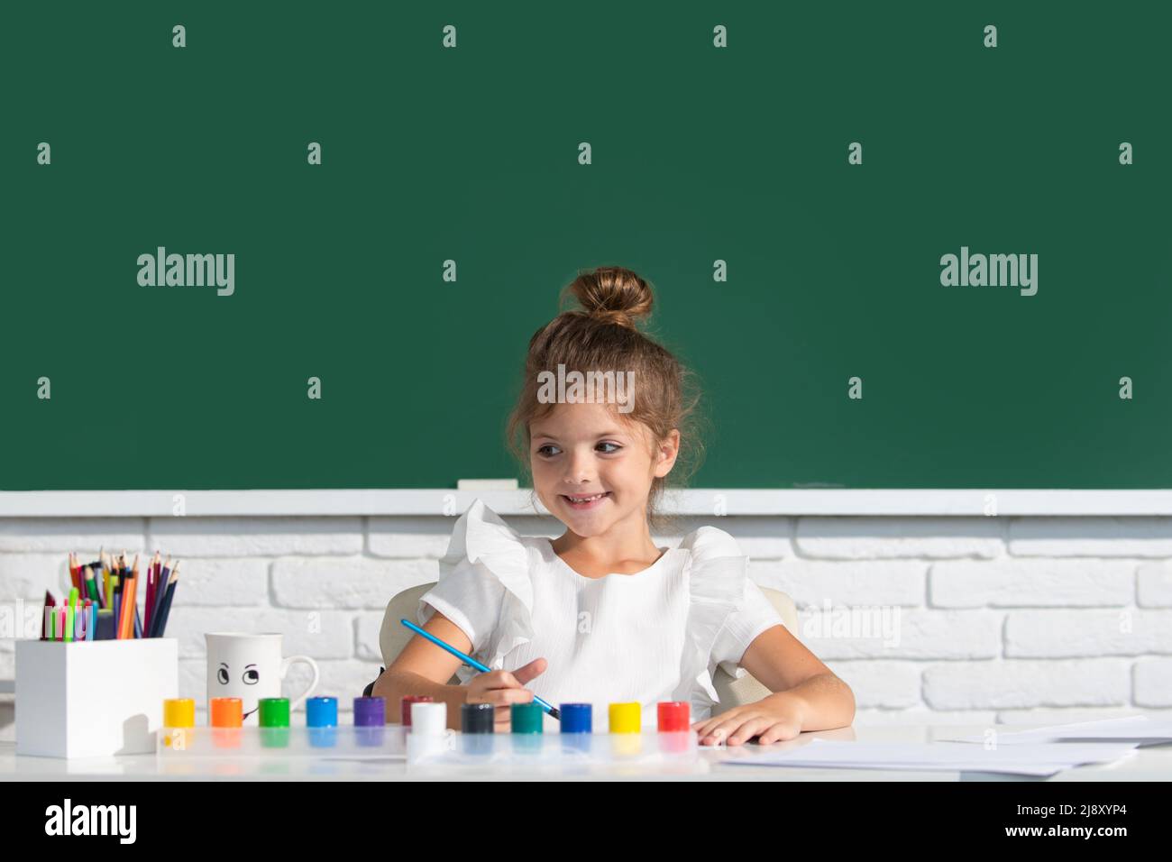 Child girl draws in classroom sitting at a table, having fun on school ...