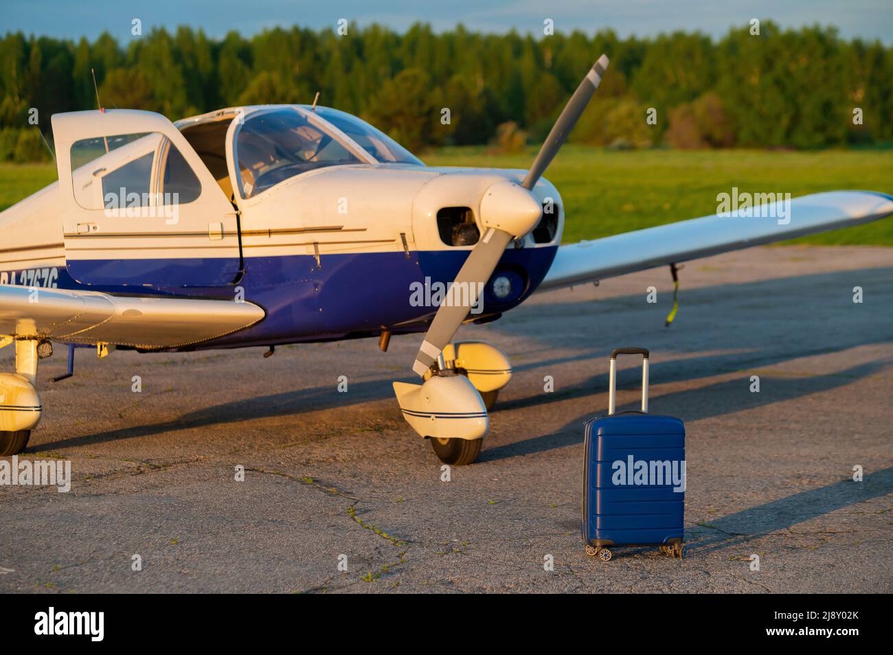 A blue suitcase and a landed small private jet. Four-seater plane with ...