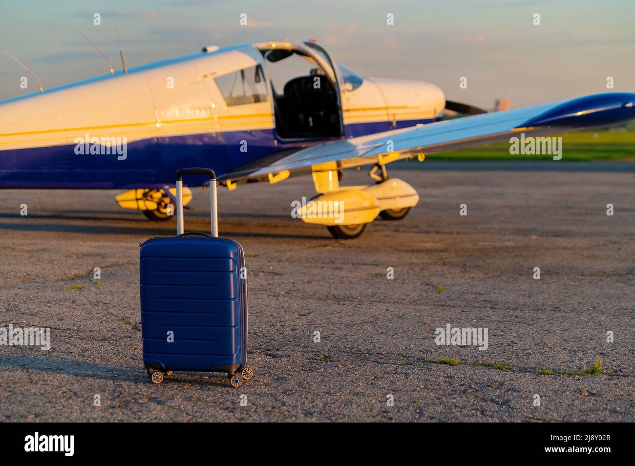 A blue suitcase and a landed small private jet. Four-seater plane with ...