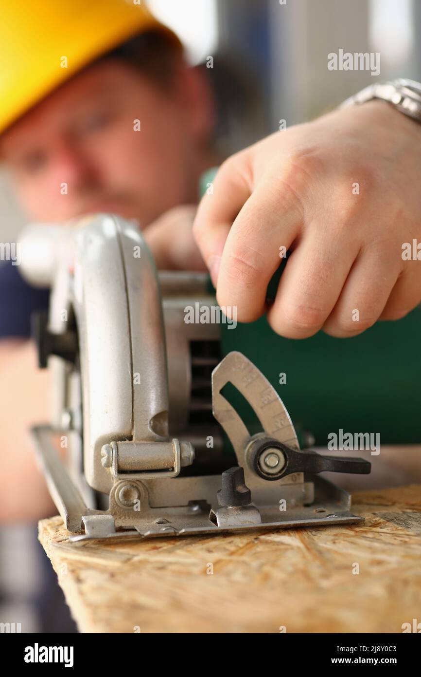 Male worker using electric saw tool, improvement on construction site ...