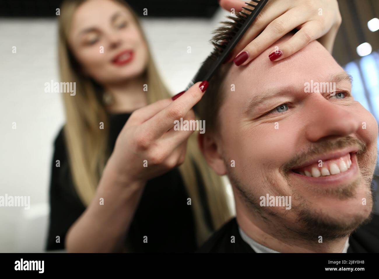 Female professional hairdresser cutting hair with scissors, smiling ...