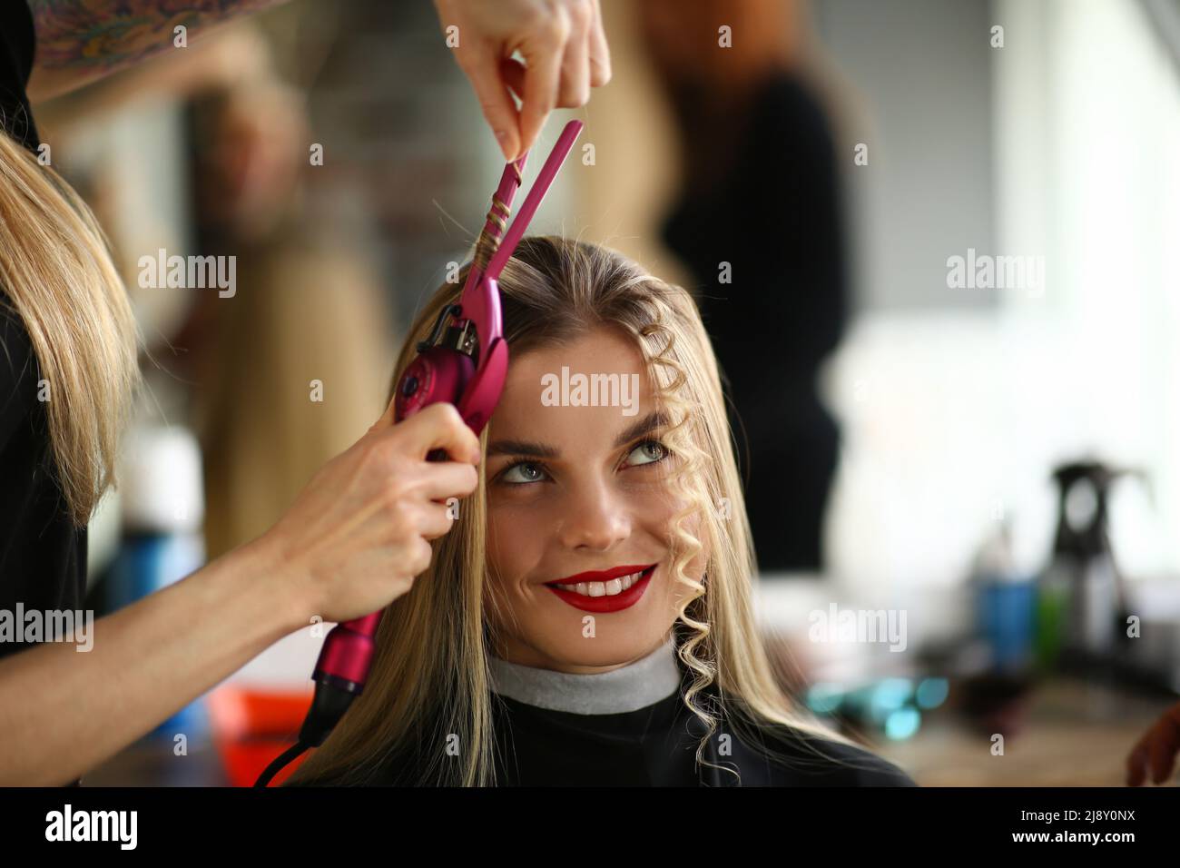 Blonde female on hairdresser appointment, master create curly hairstyle ...