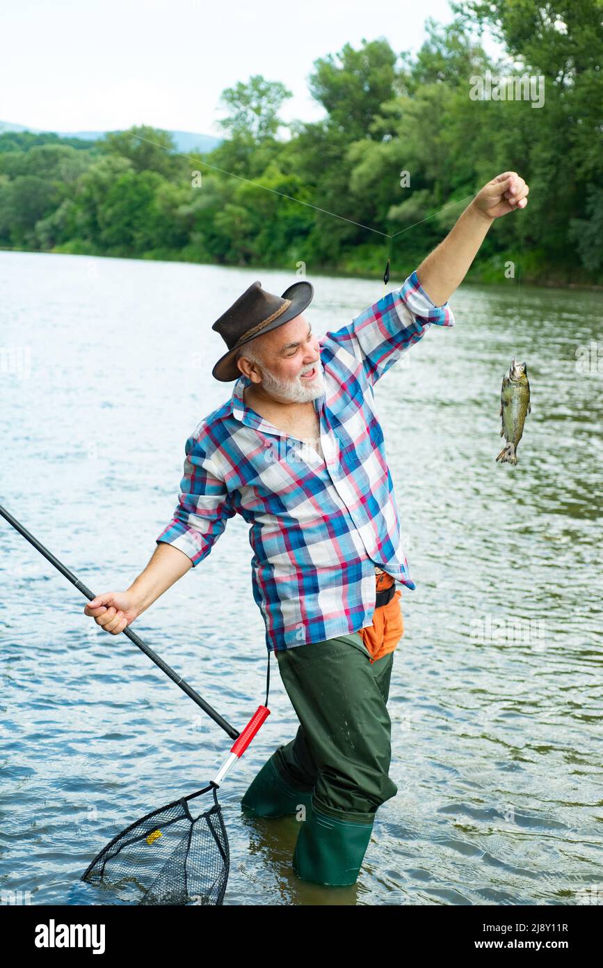 Fisherman fishing on a rever. Happy old fisherman caught a trout fish ...