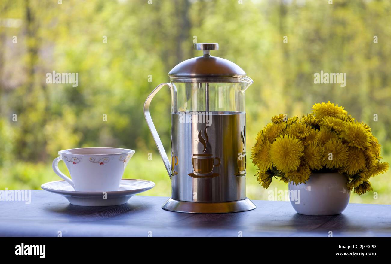 Teapot with tea and dandelion flowers. Tea in nature. Blurred ...