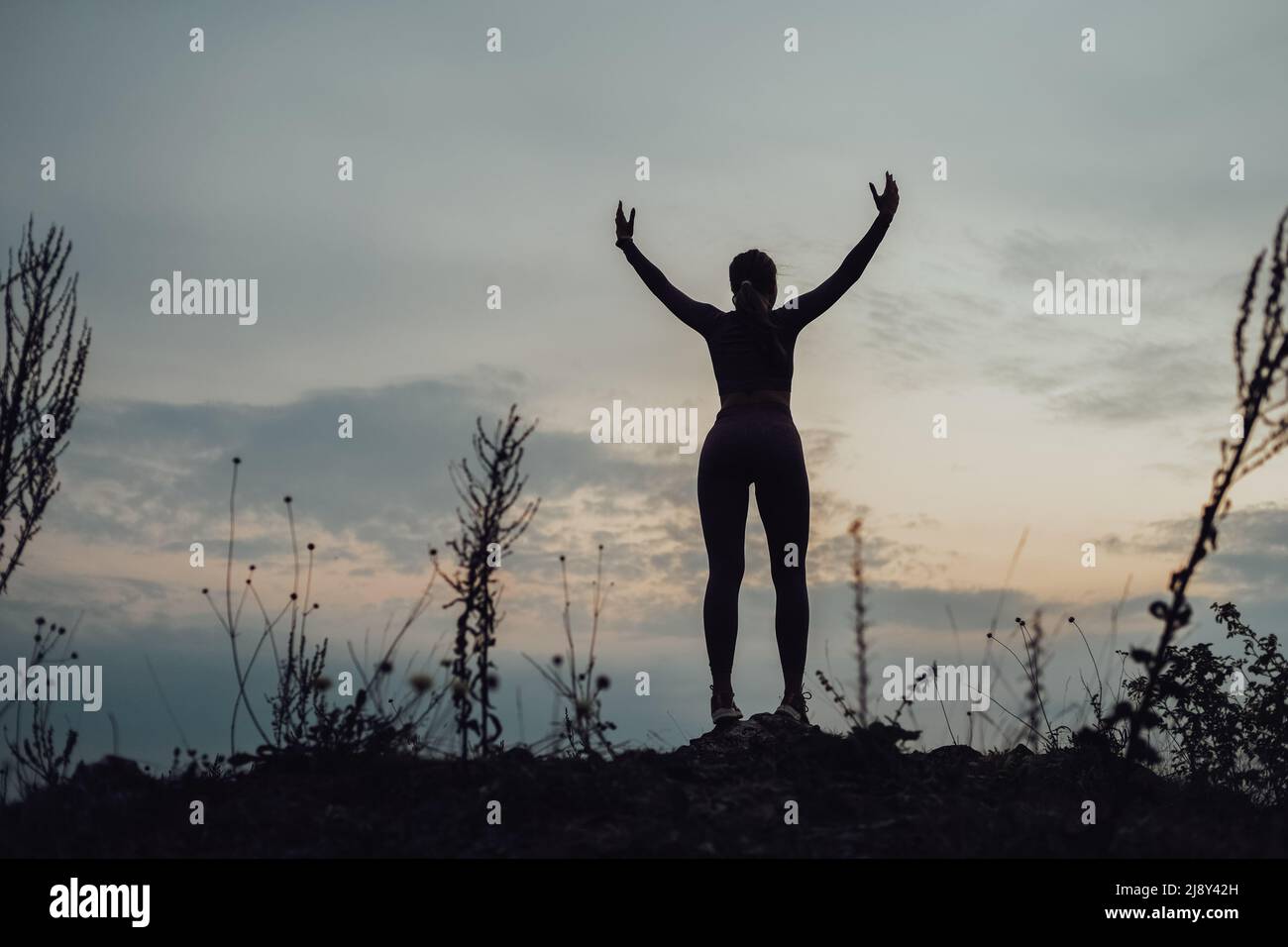 Silhouette of Sporty Young Woman Standing on Top of the Hill and Raised ...