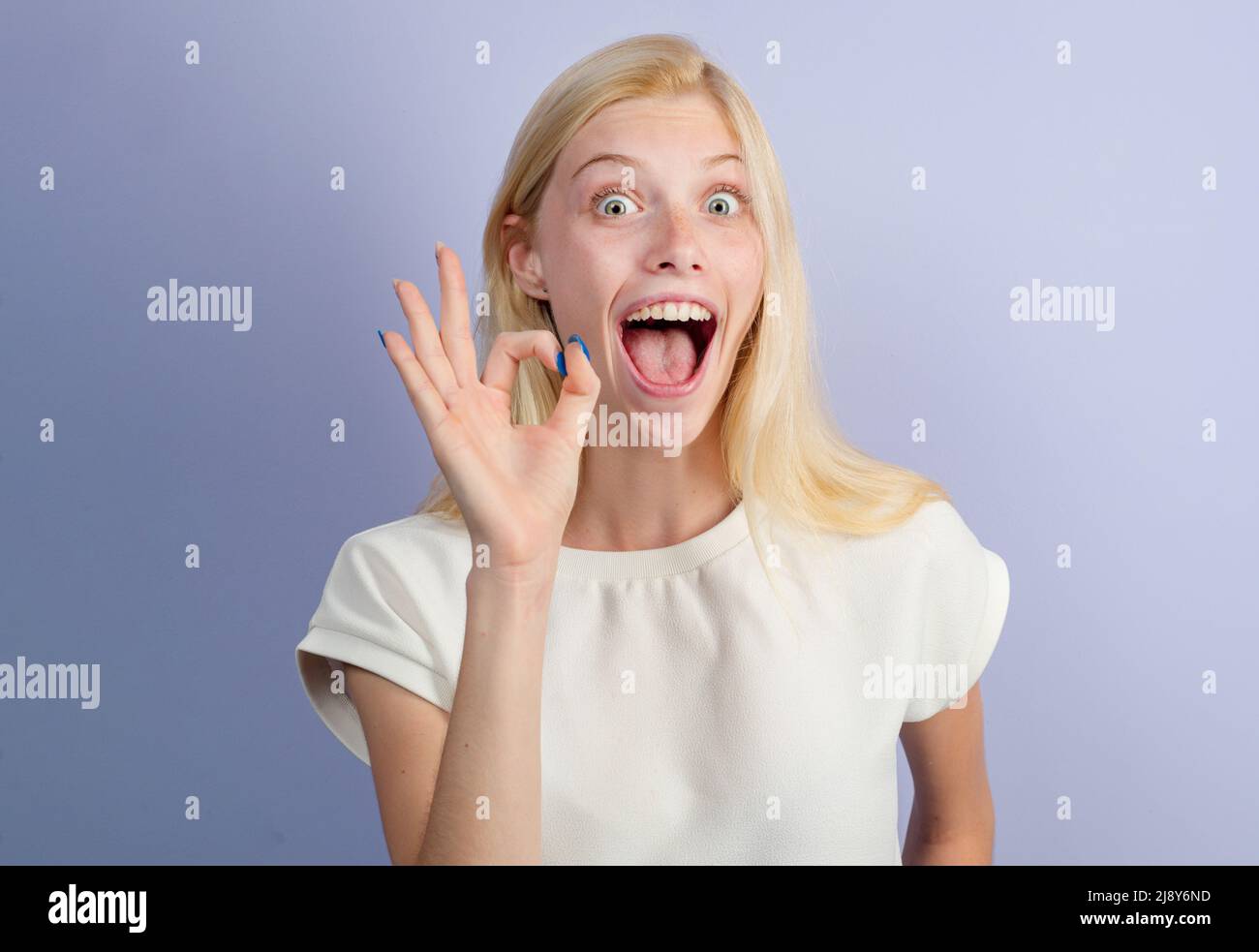 Woman on isolated background showing ok sign with fingers. Funny young ...