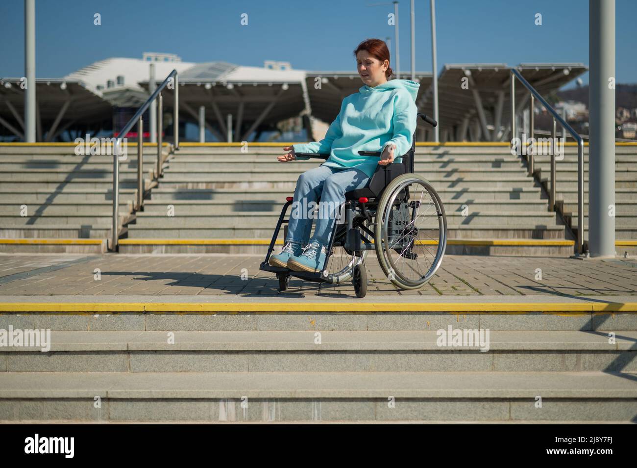 A caucasian woman in a wheelchair cannot go down stairs without a ramp ...
