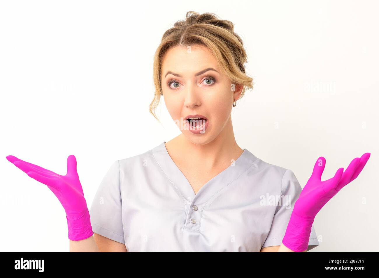 Body language. Young surprised Caucasian woman doctor wearing gloves ...
