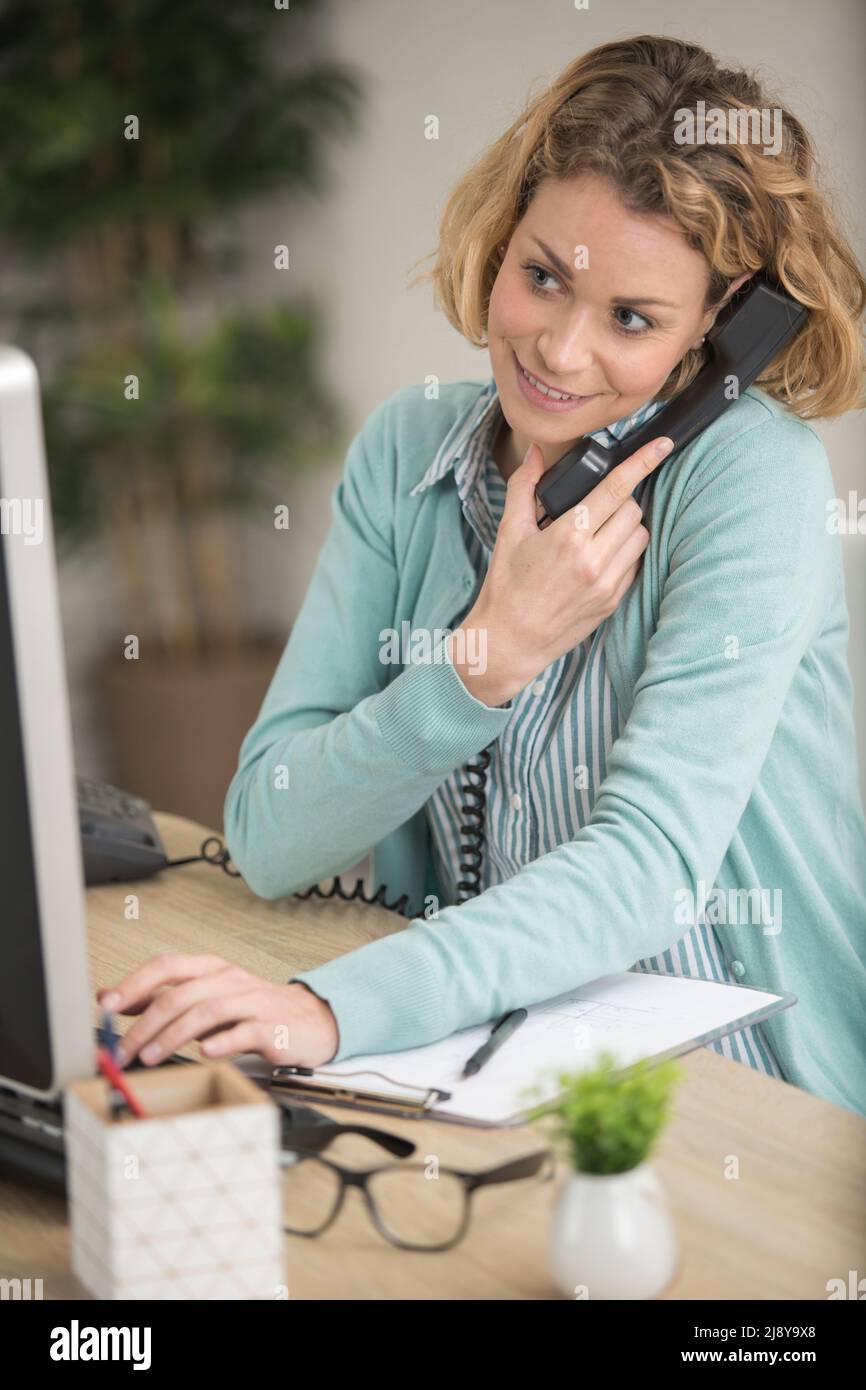 woman at office desk talking on landline Stock Photo - Alamy