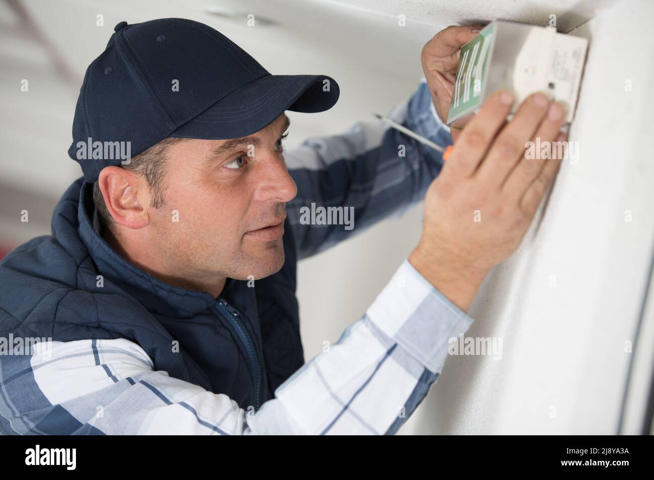 man fixing exit sign to wall Stock Photo - Alamy