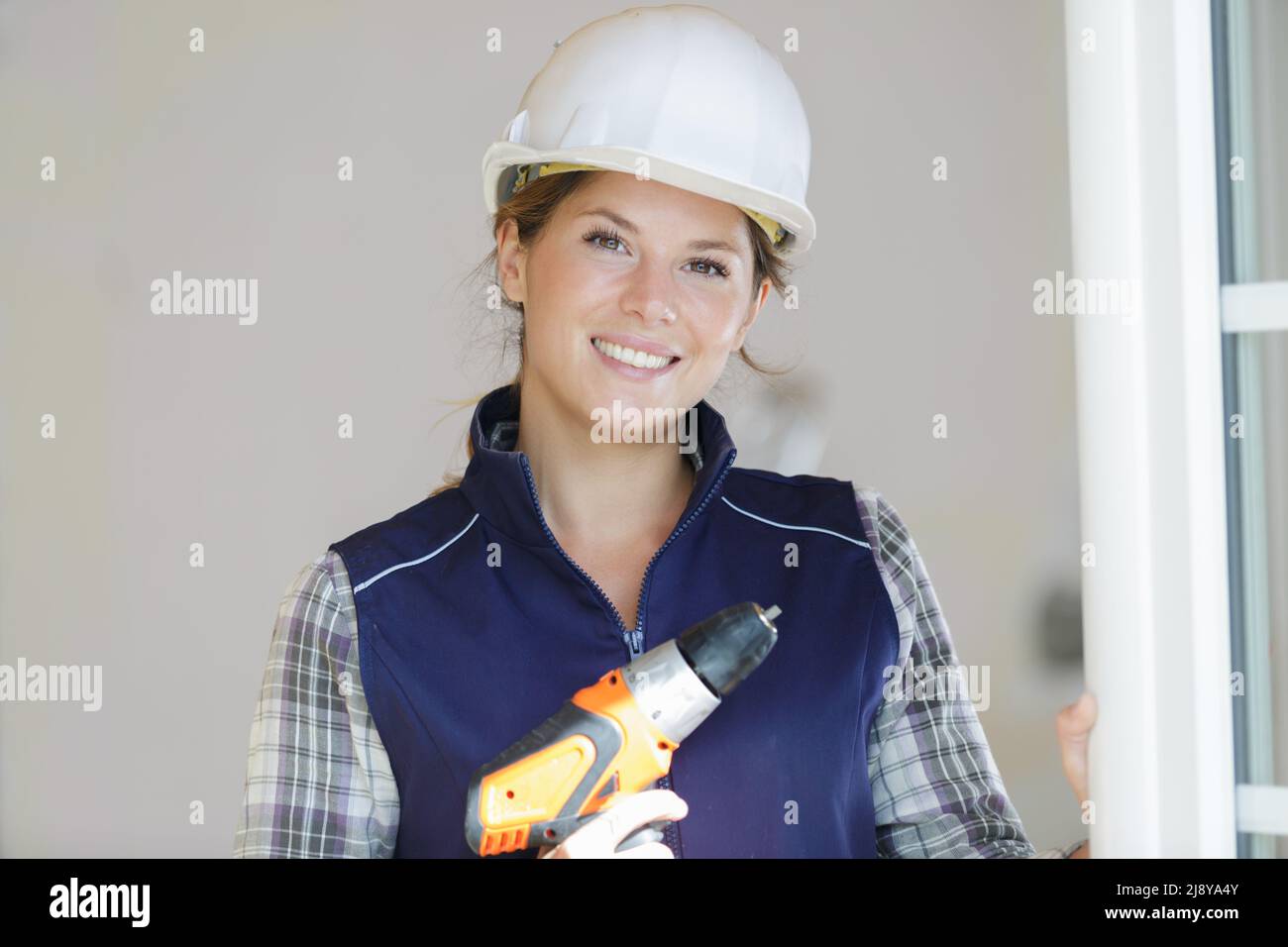 pretty young smiling woman using cordless drill Stock Photo - Alamy
