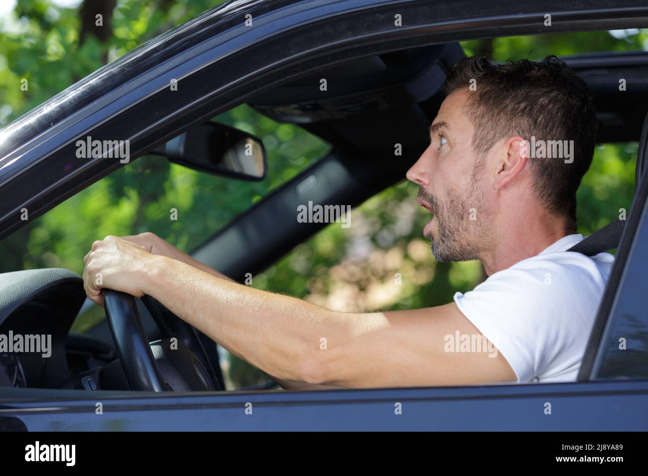 side view of man driving car with shocked expression Stock Photo - Alamy