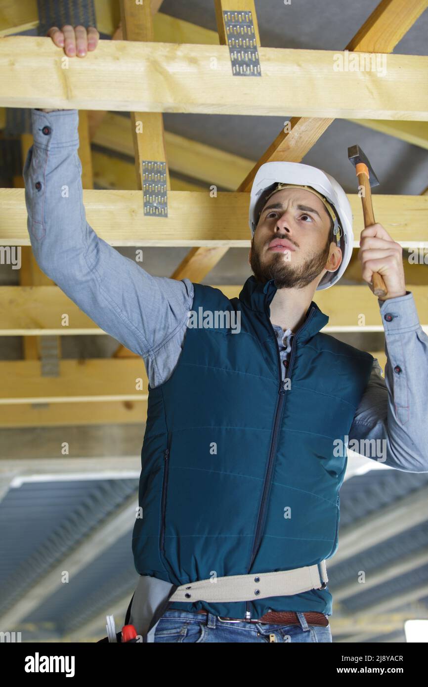 young male builder using hammer on wooden beam Stock Photo - Alamy