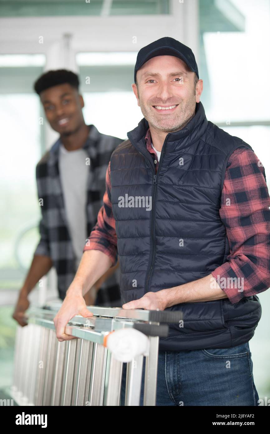 two men carrying a ladder Stock Photo - Alamy