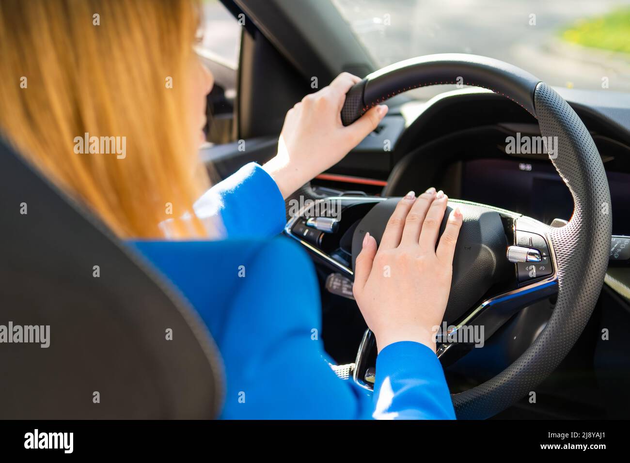 Back view of woman driving car and press down vehicle horn in blue suit ...