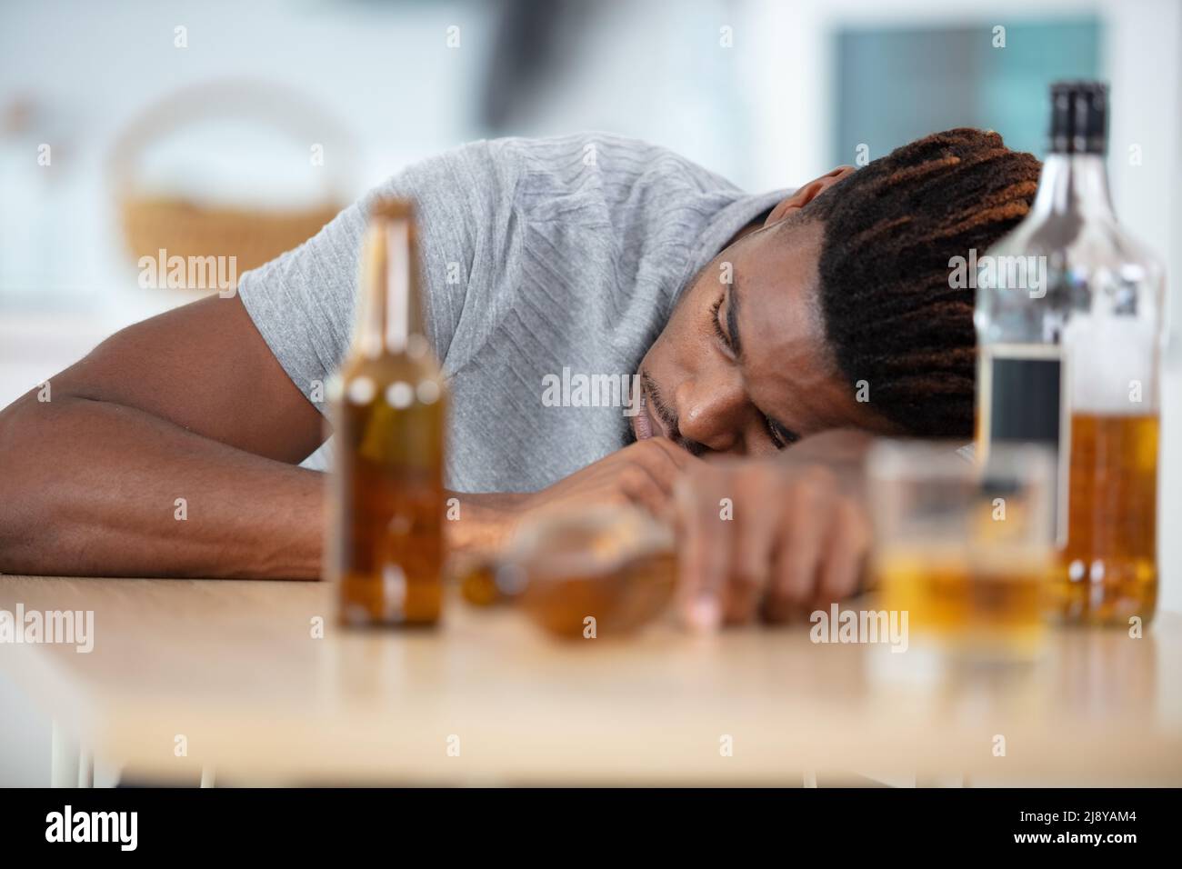 male sleeping on table surrounded by alcohol bottles Stock Photo - Alamy