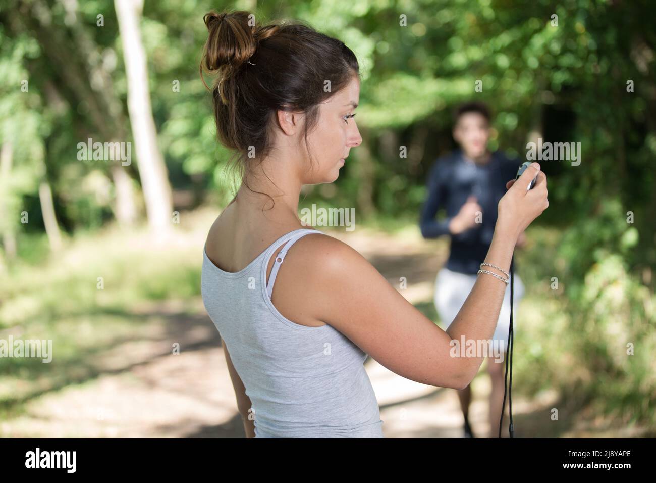 female coach timing runner in a park Stock Photo - Alamy
