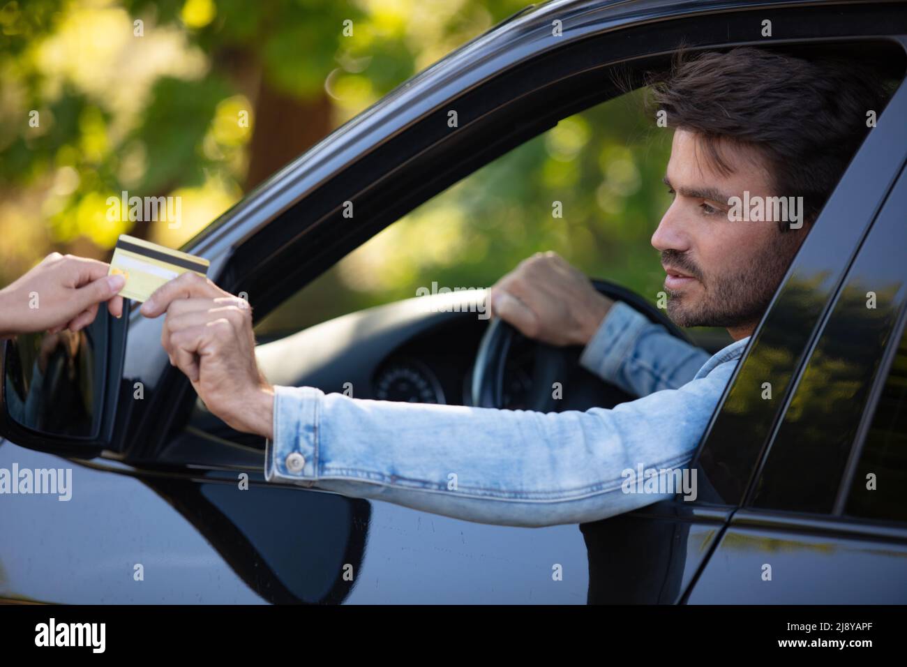 man pays money to a cashier for a toll road Stock Photo - Alamy