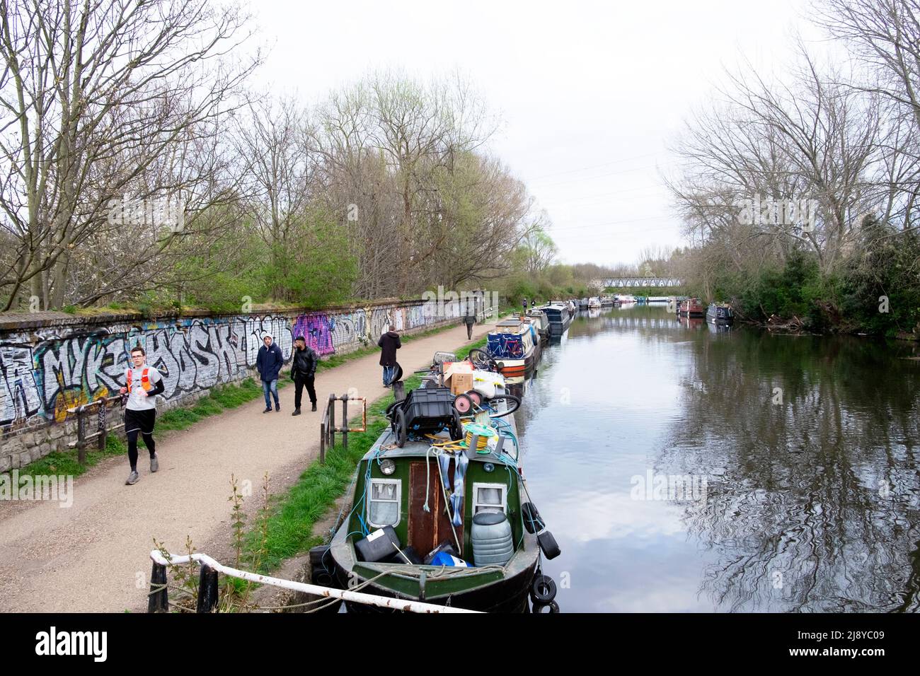 People on the cycle pedestrian path and narrowboats along the River Lea ...
