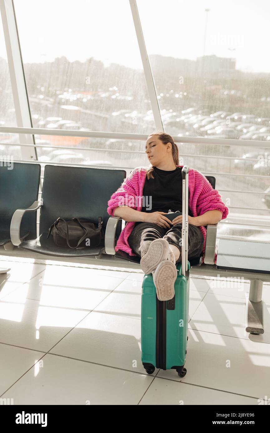 Portrait of tired woman wearing pink cardigan, sitting on chair ...