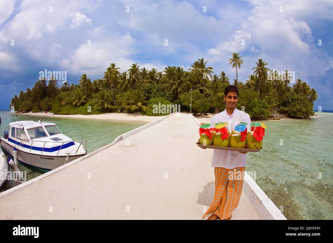 Maldivian waiter serves on the jetty welcome drinks for new arrivals ...