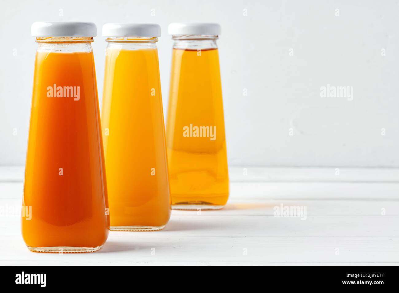 Glass bottles of different juices on white background Stock Photo - Alamy