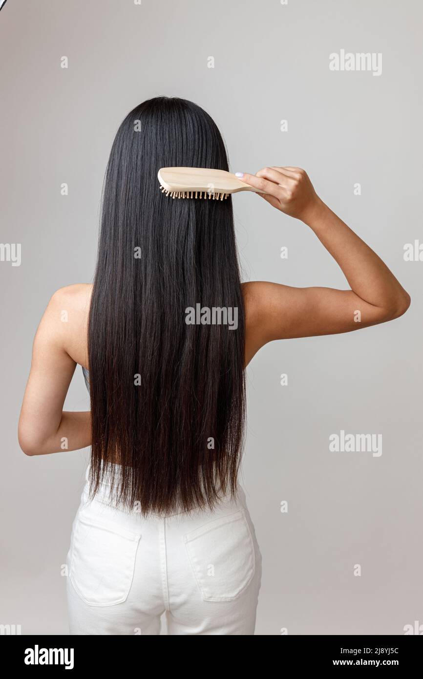 Young woman brushing long hair in studio Stock Photo - Alamy